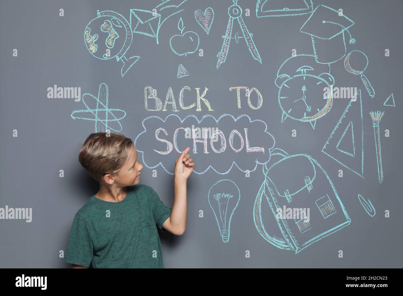 Little child near drawings and text BACK TO SCHOOL on grey background ...