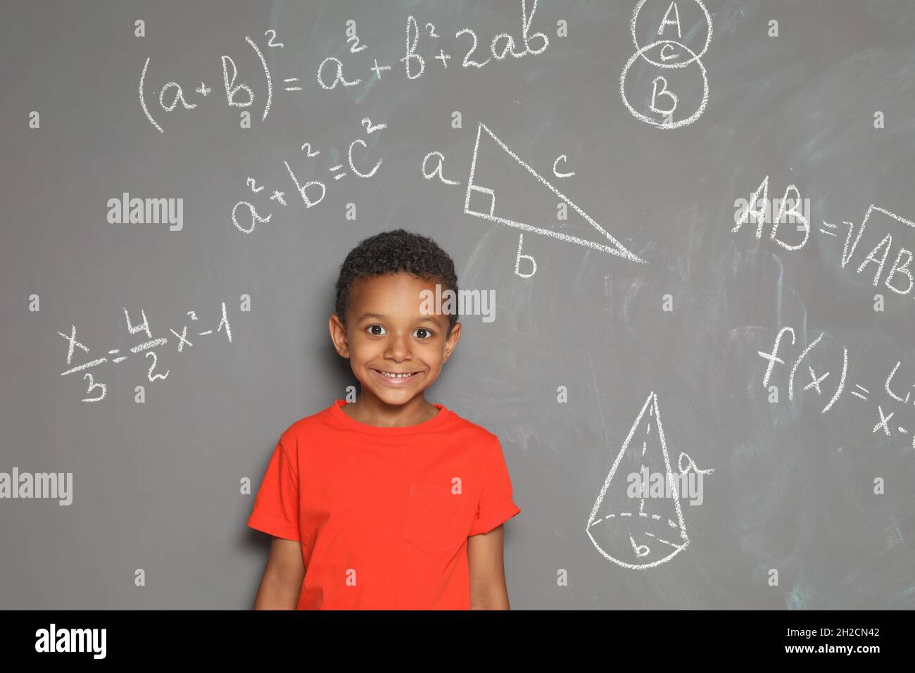 Little African-American school child and mathematical formulas on grey ...