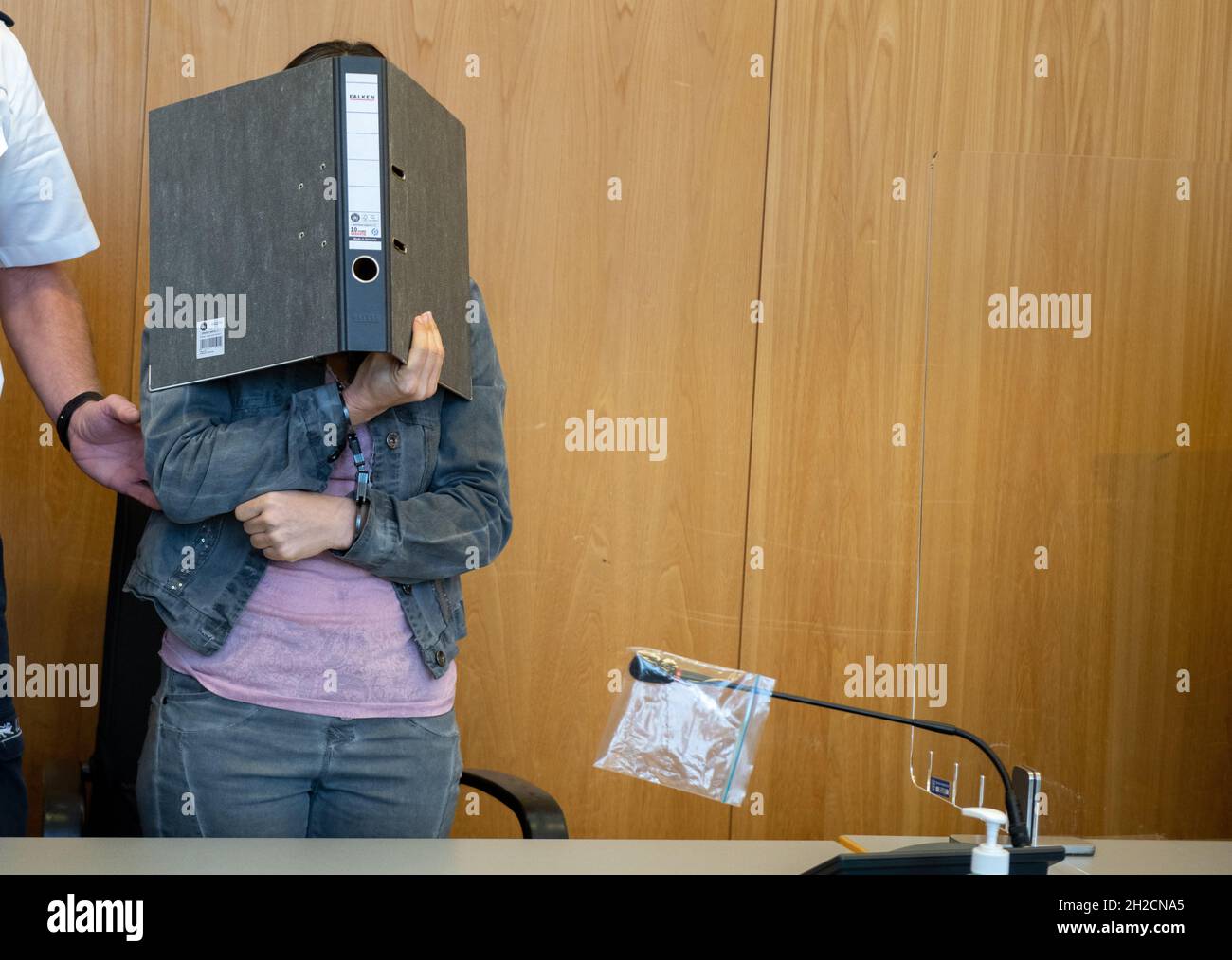 Ulm, Germany. 21st Oct, 2021. The defendant covers her face with a file ...
