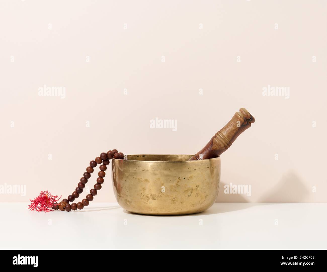 copper singing bowl and wooden clapper on a white table. Musical ...