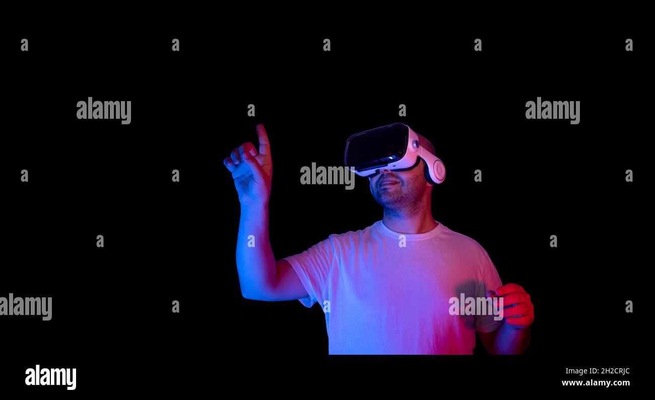 Young man using vr glasses in black background and neon light ...