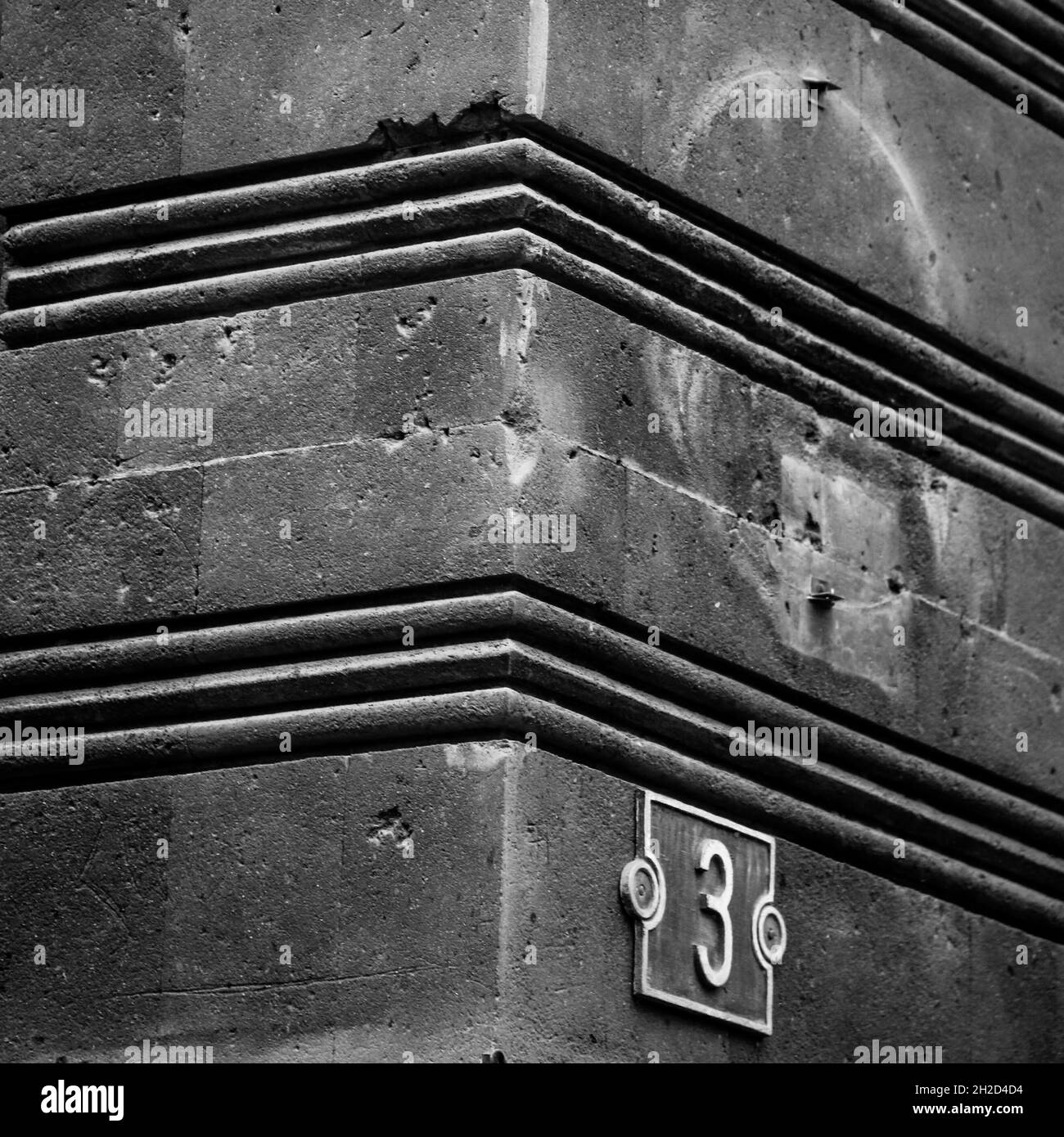 Grayscale shot of a building number sign on a wall in the daylight ...