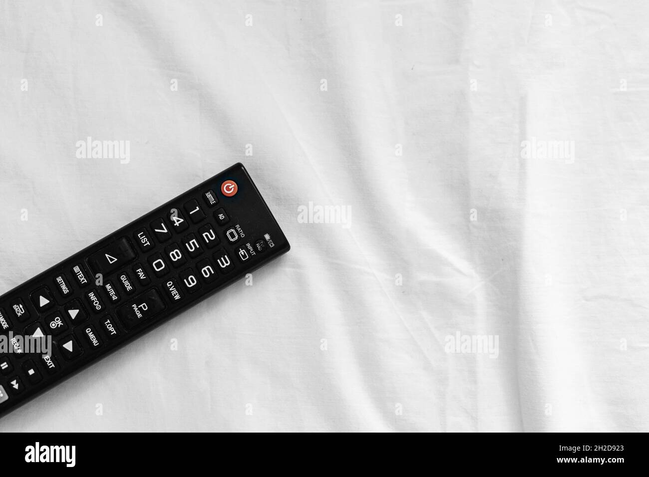 Black TV remote on a bed in a hotel Stock Photo - Alamy