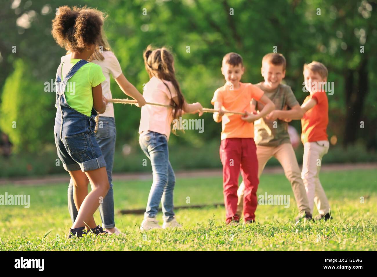 Cute little children playing with rope outdoors on sunny day Stock ...