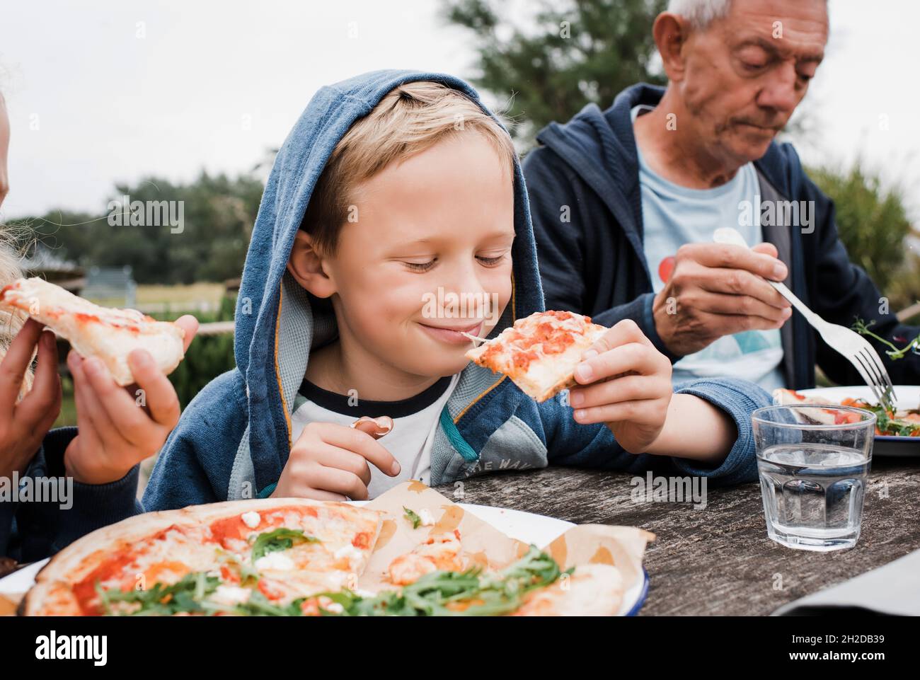 boy happily eating pizza with his family outside in the garden Stock ...