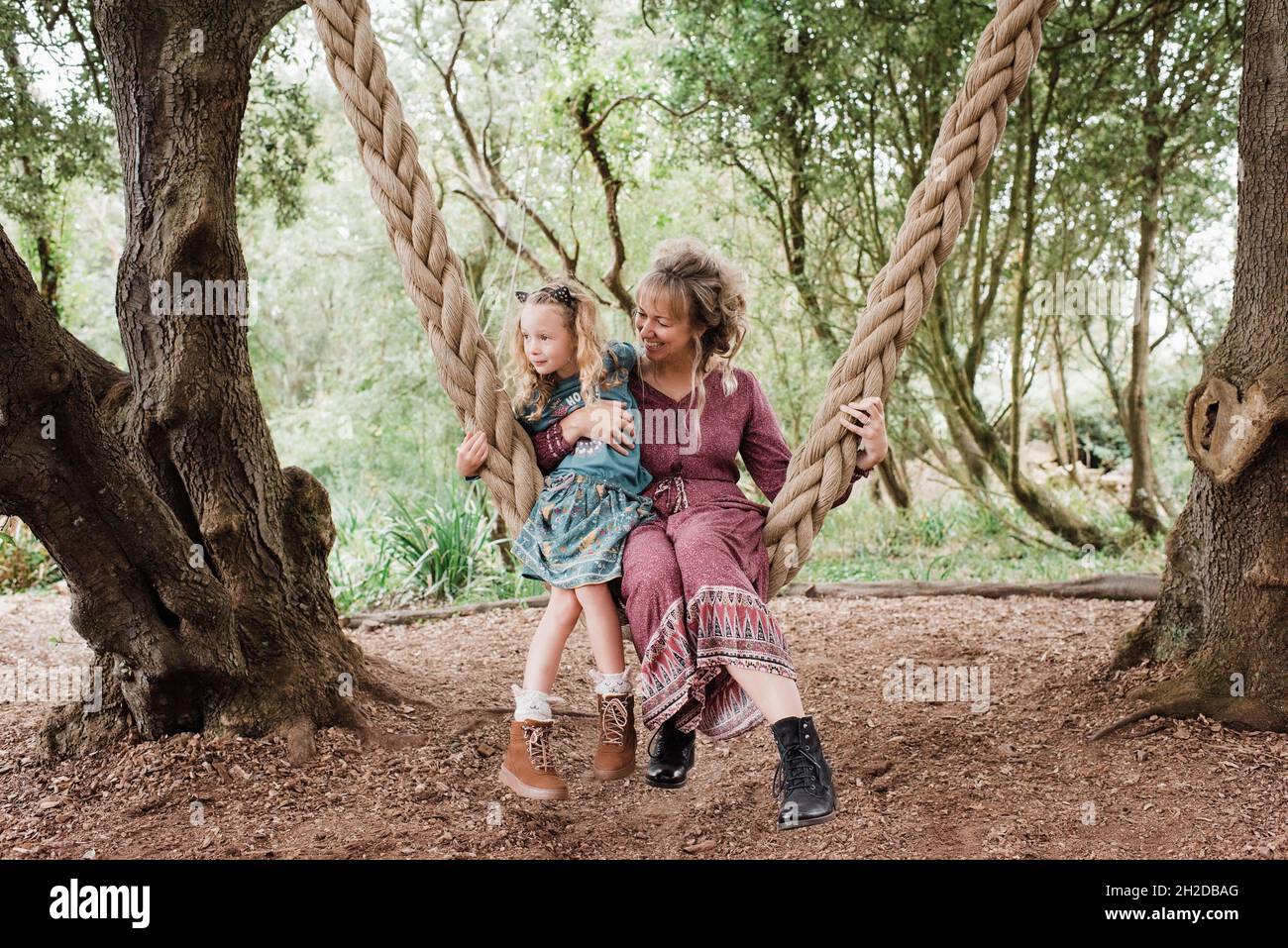 mother and daughter sat on an outdoor swing together hugging Stock ...