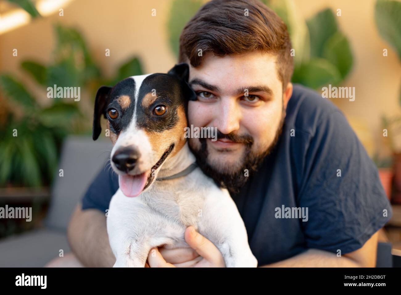 Friendly young man hugging his cute grocer dog with both hands and ...