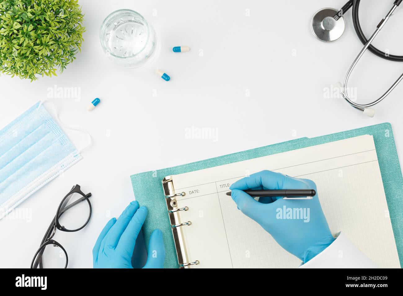 Doctor at his desk writes in a notebook Stock Photo - Alamy