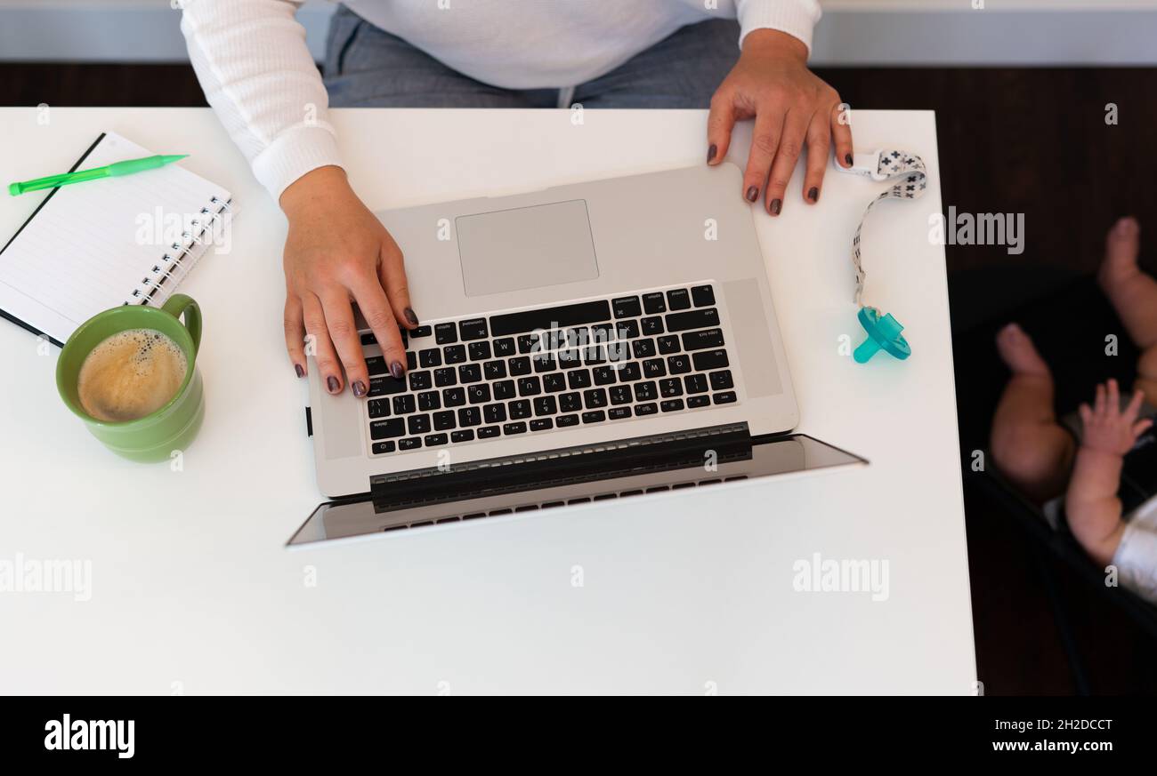 Overview of working mom on laptop with baby Stock Photo - Alamy