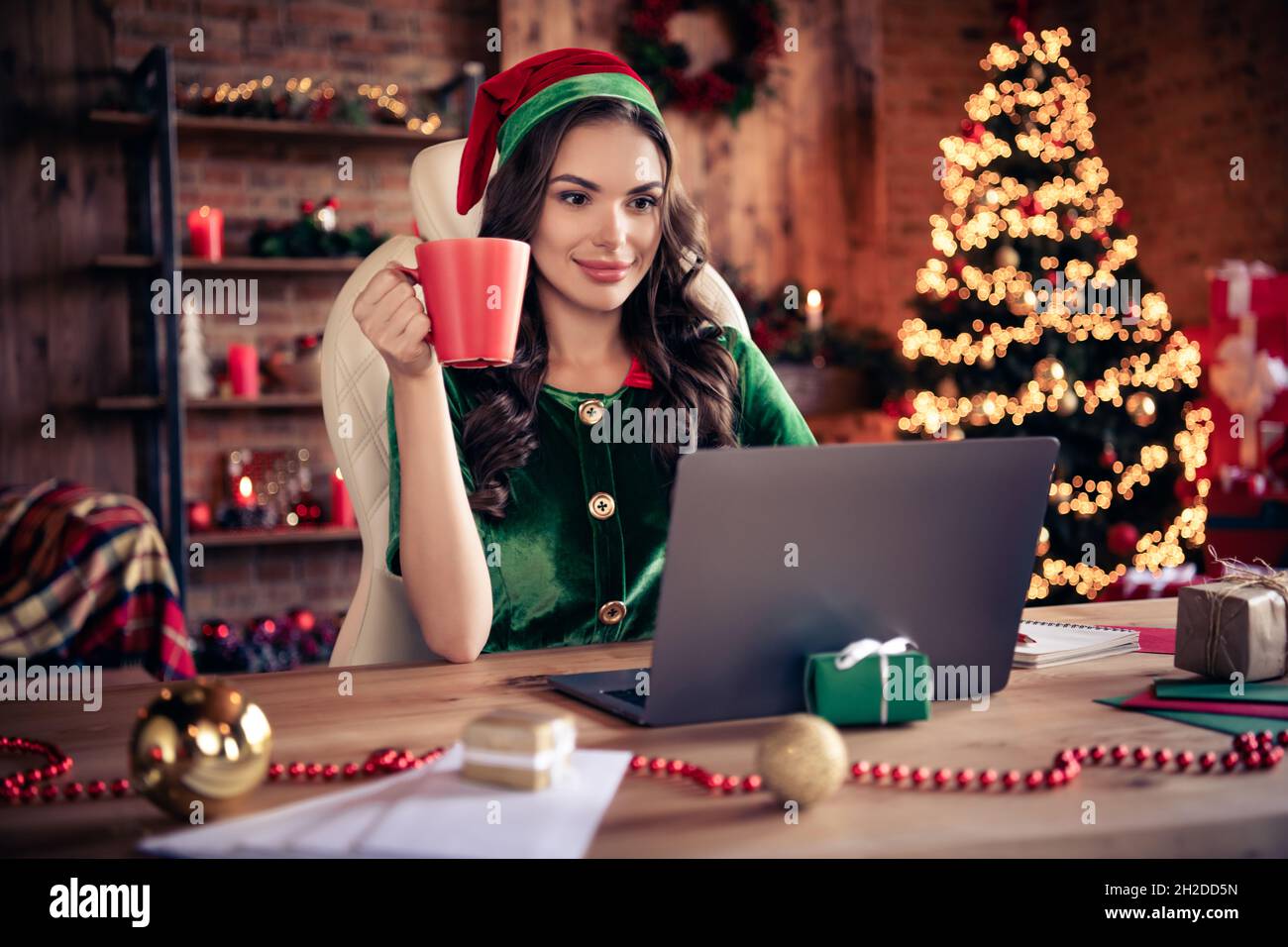 Portrait of beautiful cheerful girl elf using pc drinking cacao ...