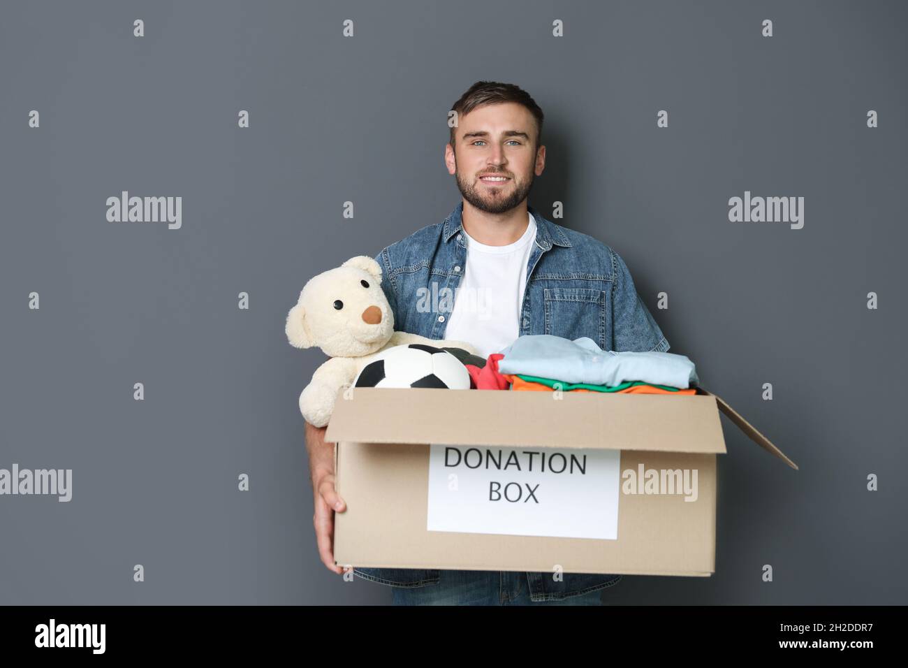 Young man holding box with donations on grey background Stock Photo - Alamy