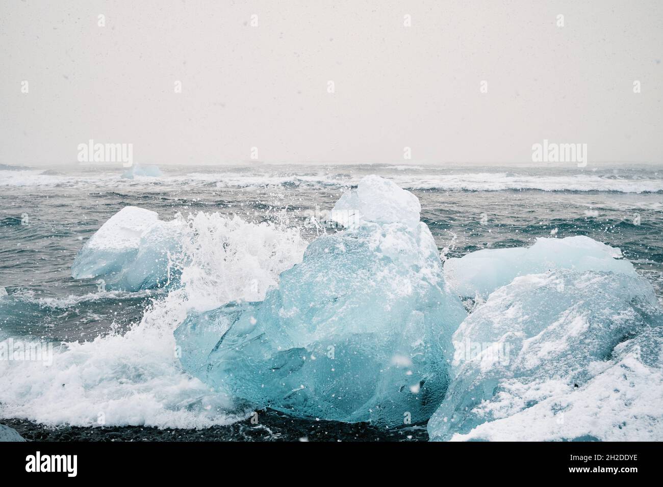 Scenic view of ice pieces in wavy sea with splashing foam under light ...