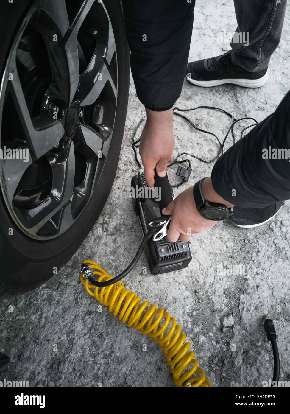 Adult man inflates car tires with compressor Stock Photo - Alamy