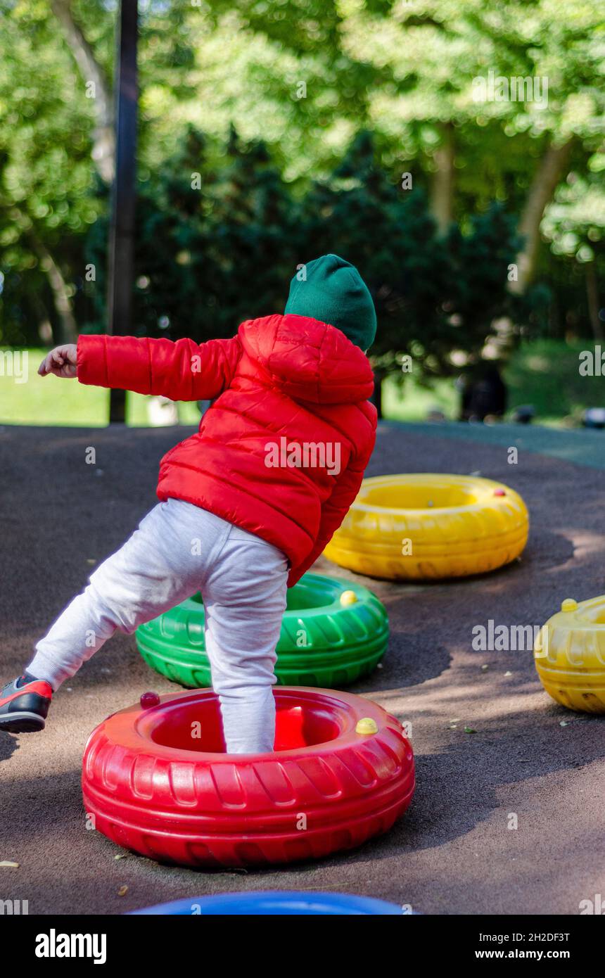 boy in red jacket jumping over colored tires Stock Photo - Alamy