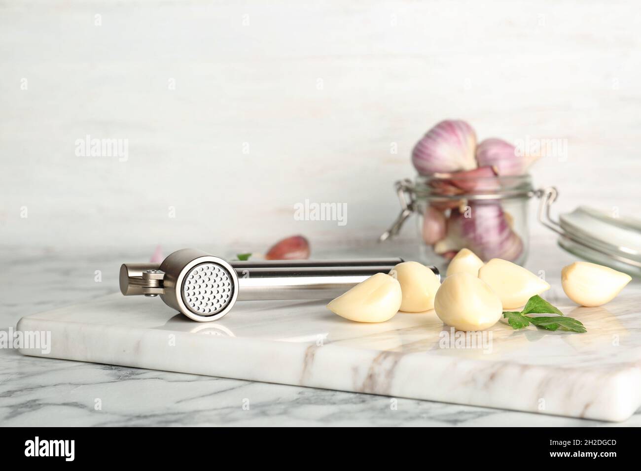 Garlic press and cloves on marble board. Kitchen utensil Stock Photo ...