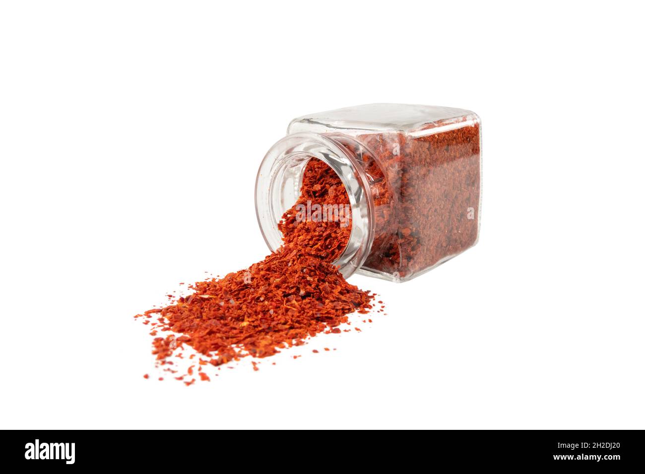 chilli pepper seedless flakes pouring out of a glass jar isolated on ...