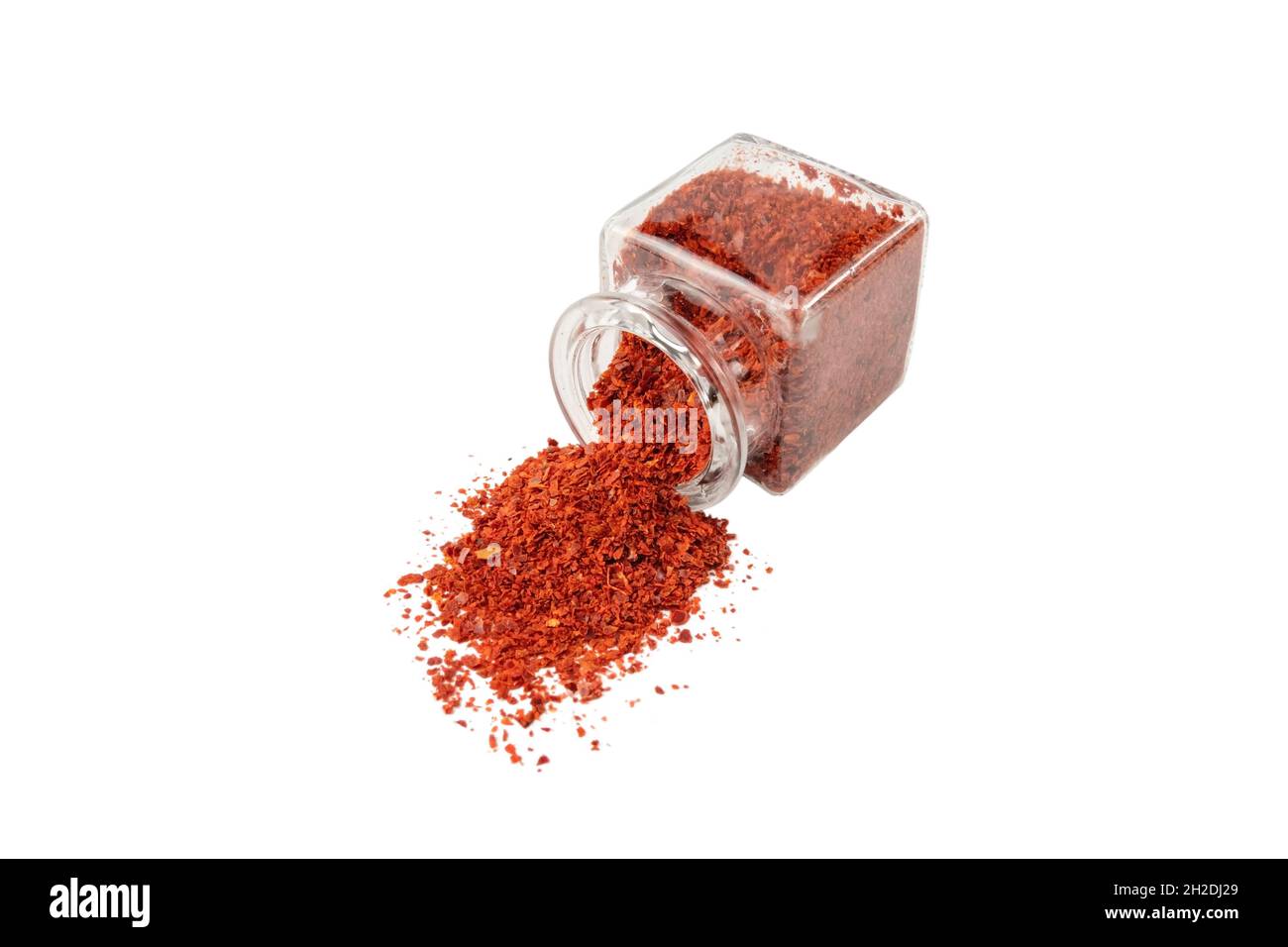 chilli pepper seedless flakes pouring out of a glass jar isolated on ...
