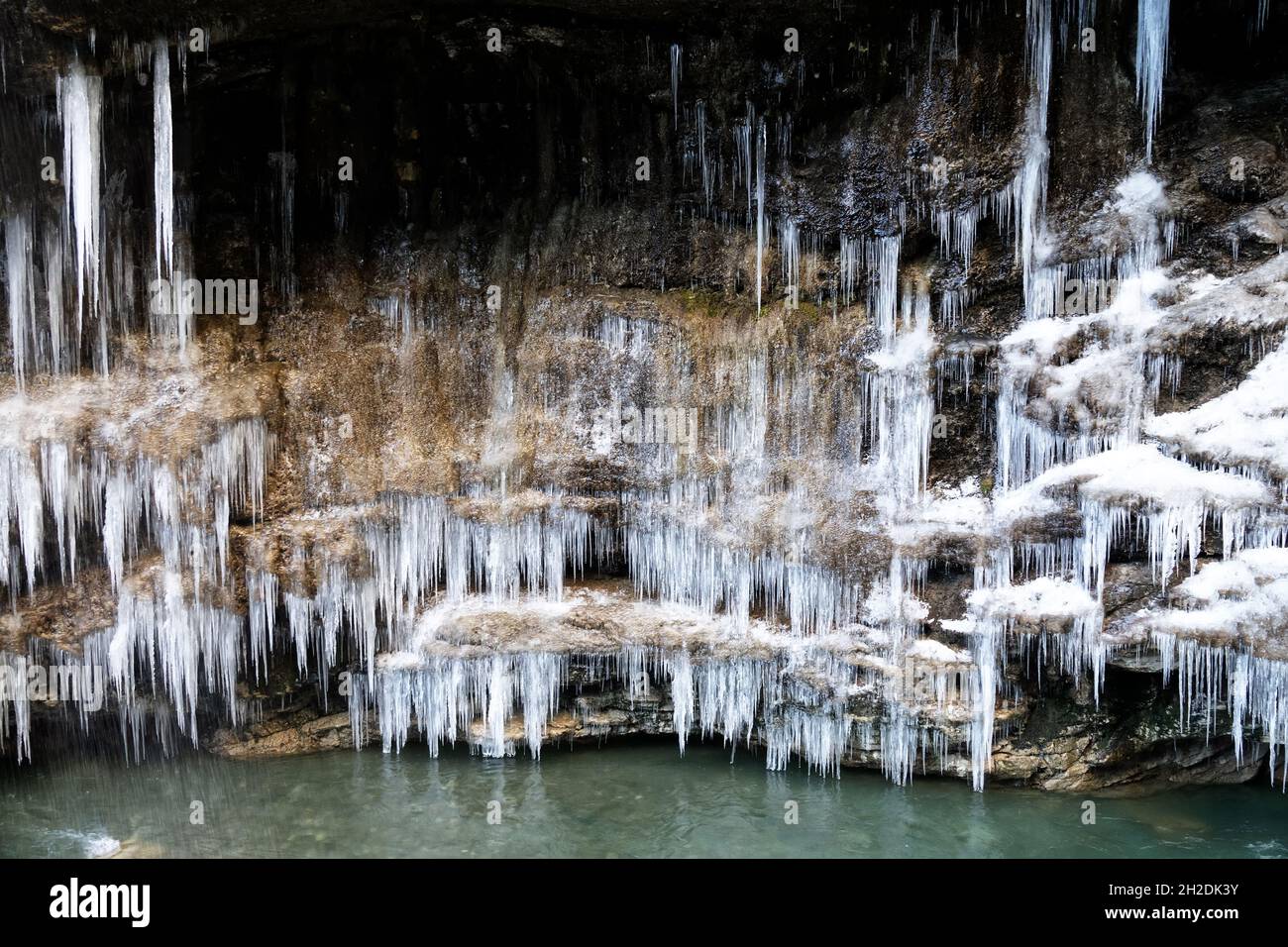 Waterfall in winter. Water jets freeze and icicles form. Attractive ice ...