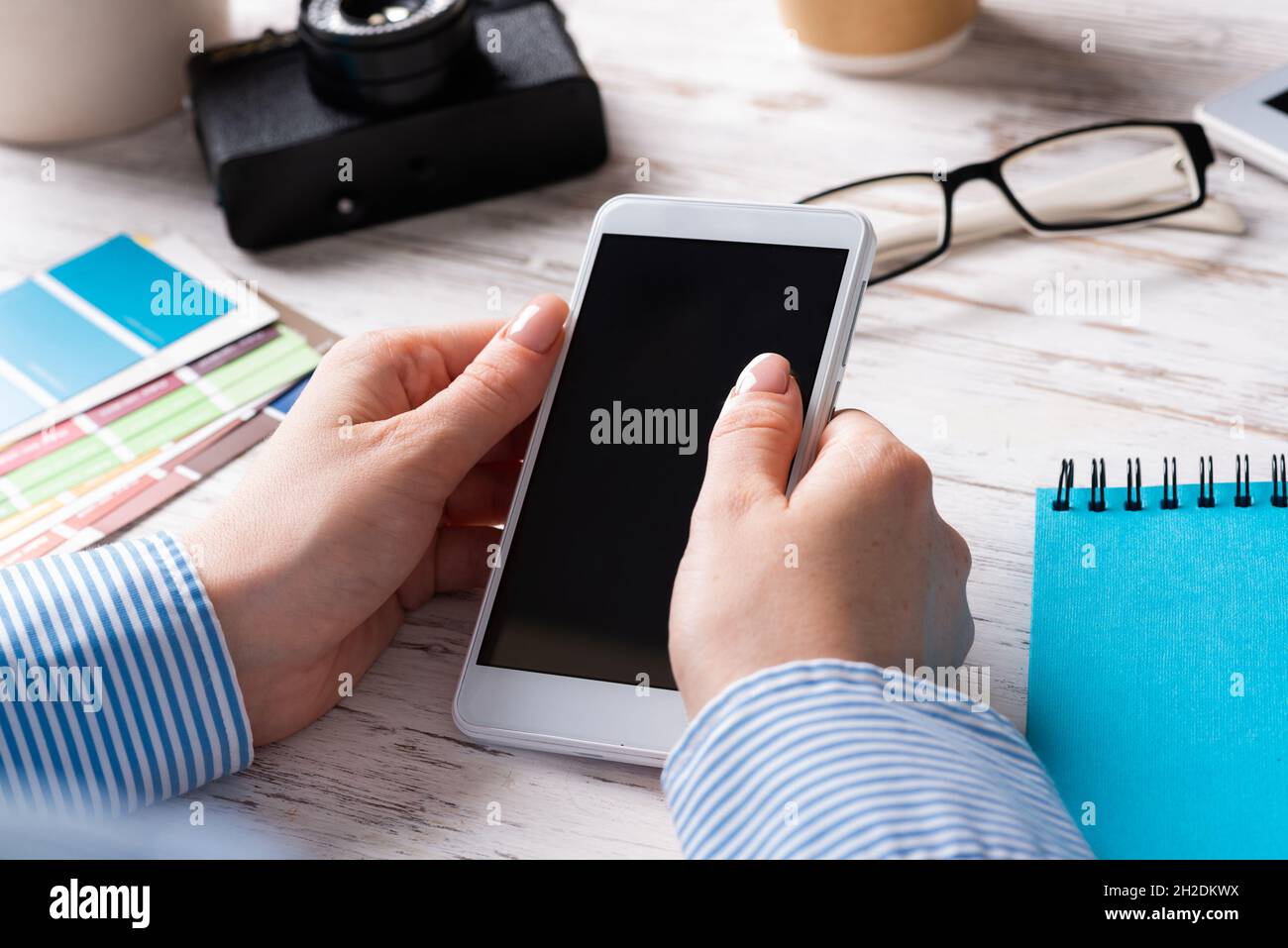 Blogger sitting at desk and holding smartphone Stock Photo - Alamy
