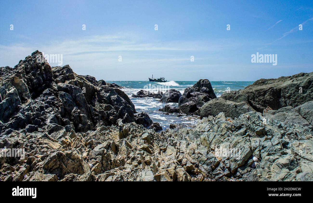 Fishing ship among the rocks Stock Photo - Alamy