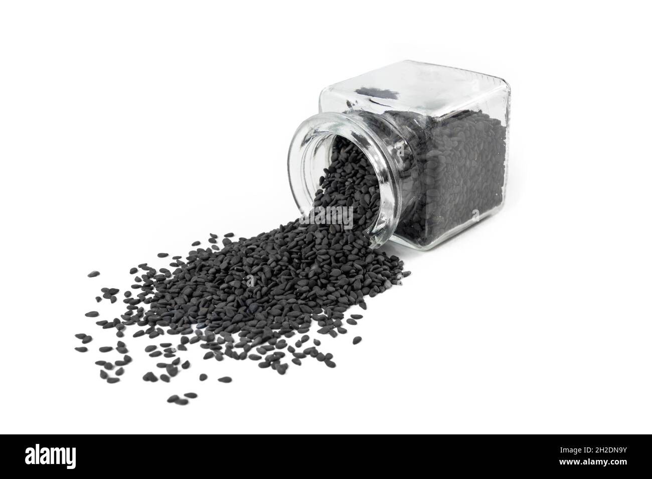 Black Sesame seeds pouring out of a glass jar isolated on white ...