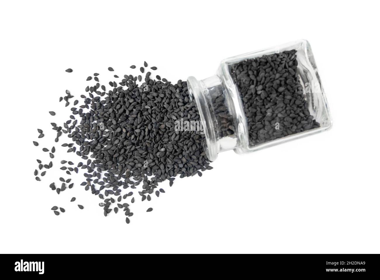 Black Sesame seeds pouring out of a glass jar isolated on white ...