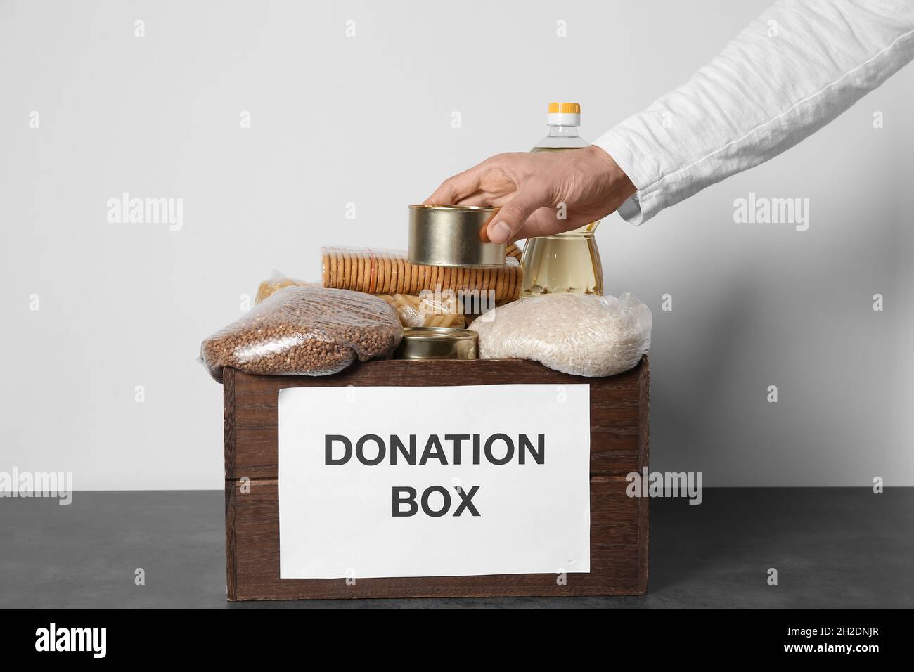 Male volunteer collecting food into donation box Stock Photo - Alamy
