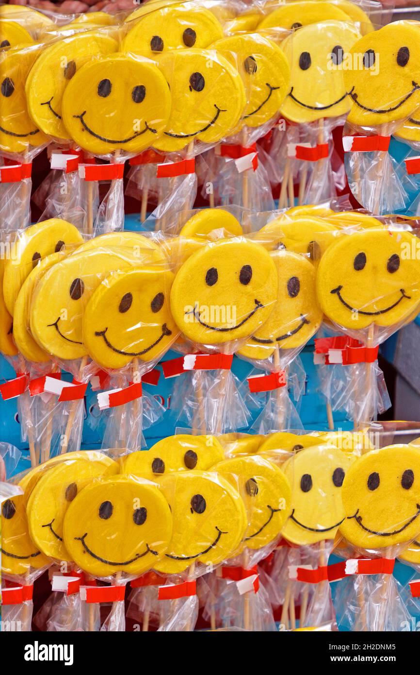 Yellow circle smiley faces lollipops sold on country fair market Stock ...