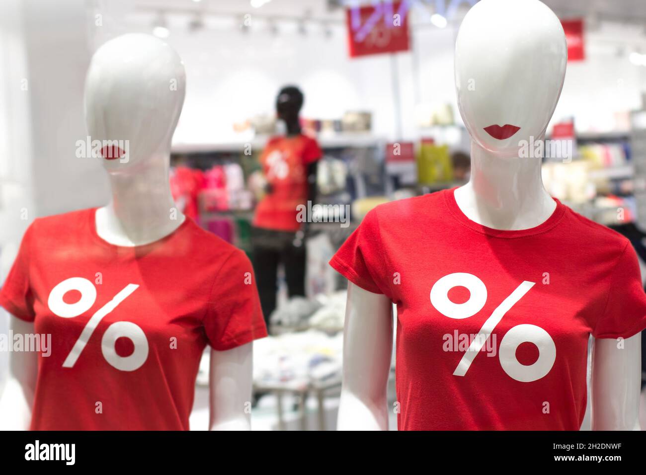 Two female mannequins in red T-shirts with a percent sign. White ...