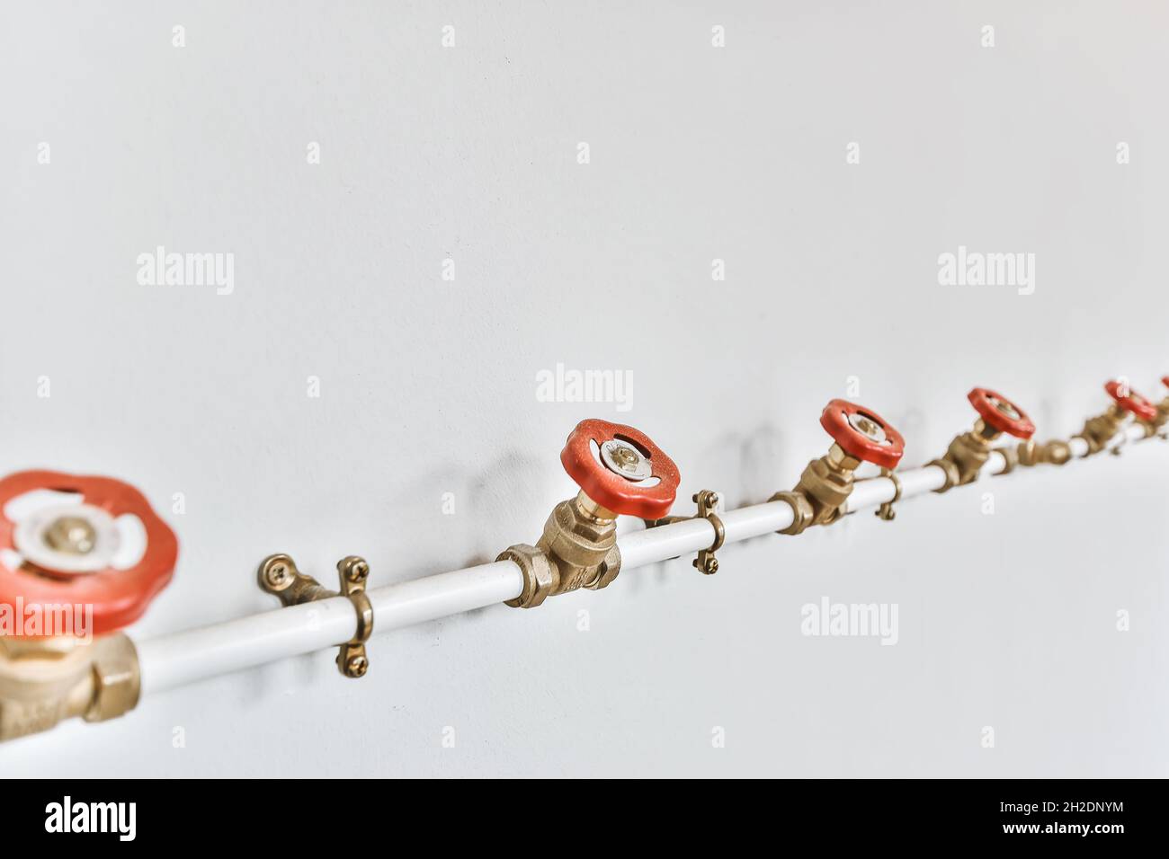 White water pipe with red valves in a row Stock Photo - Alamy