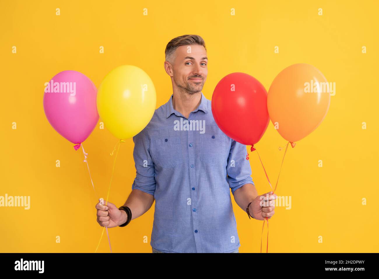 smiling handsome man hold balloons on yellow background, holiday Stock ...