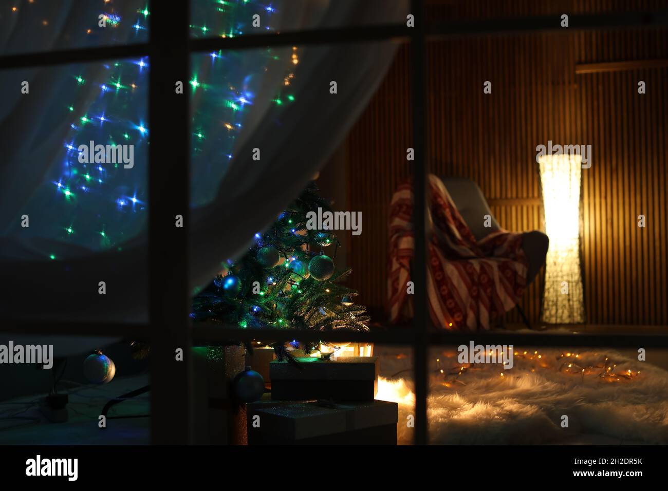 Stylish living room interior with decorated Christmas tree at night ...