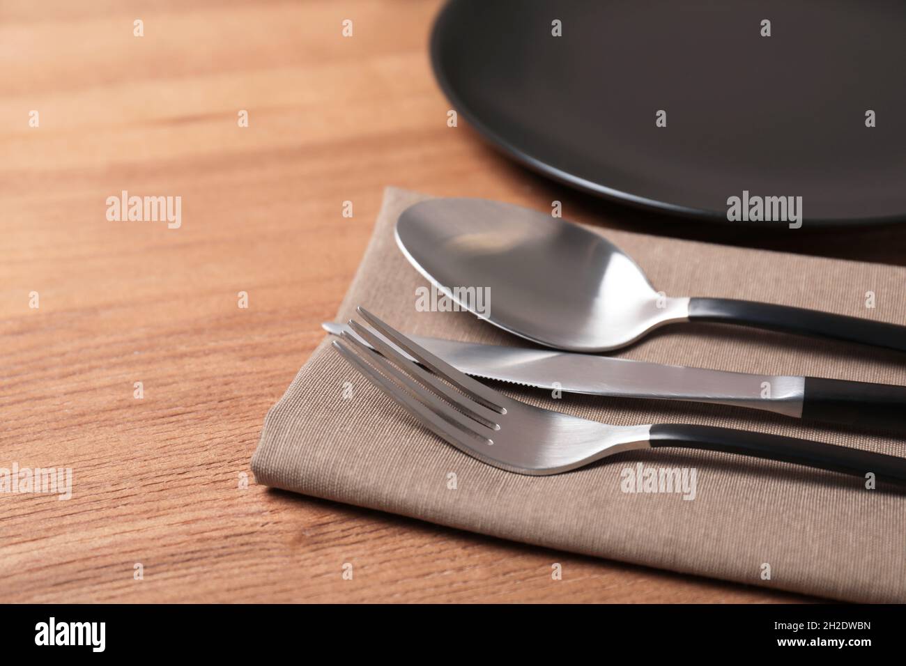 Table setting with cutlery, napkin and plate on wooden background ...