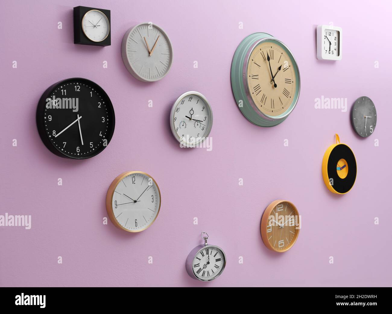 Many different clocks hanging on color wall. Time of day Stock Photo ...