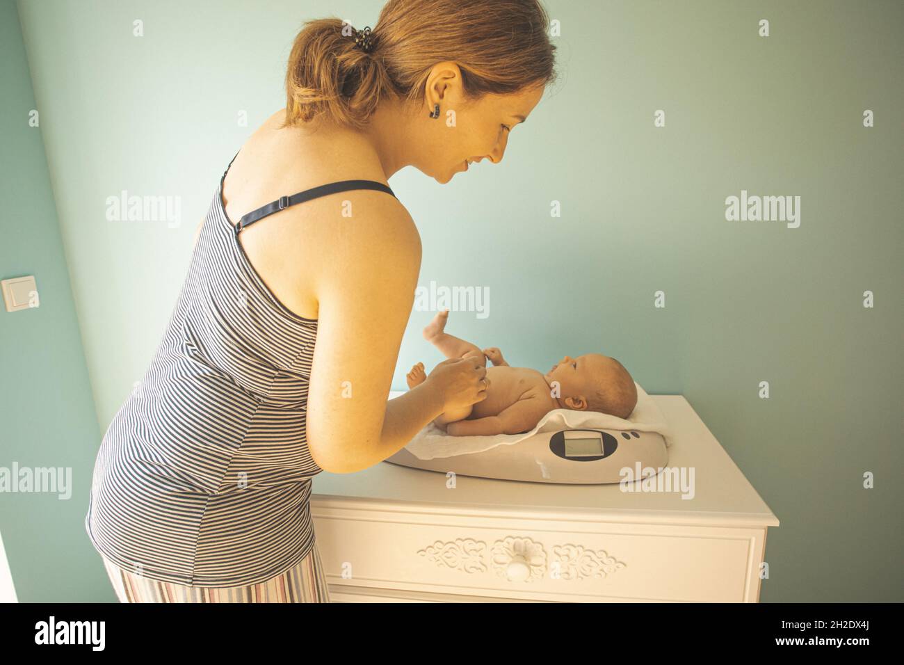 Mother weighs her newborn baby at home scales Stock Photo - Alamy