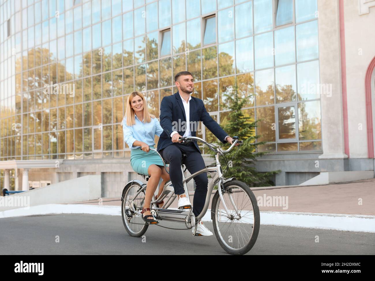 Couple riding tandem bike on city street Stock Photo - Alamy