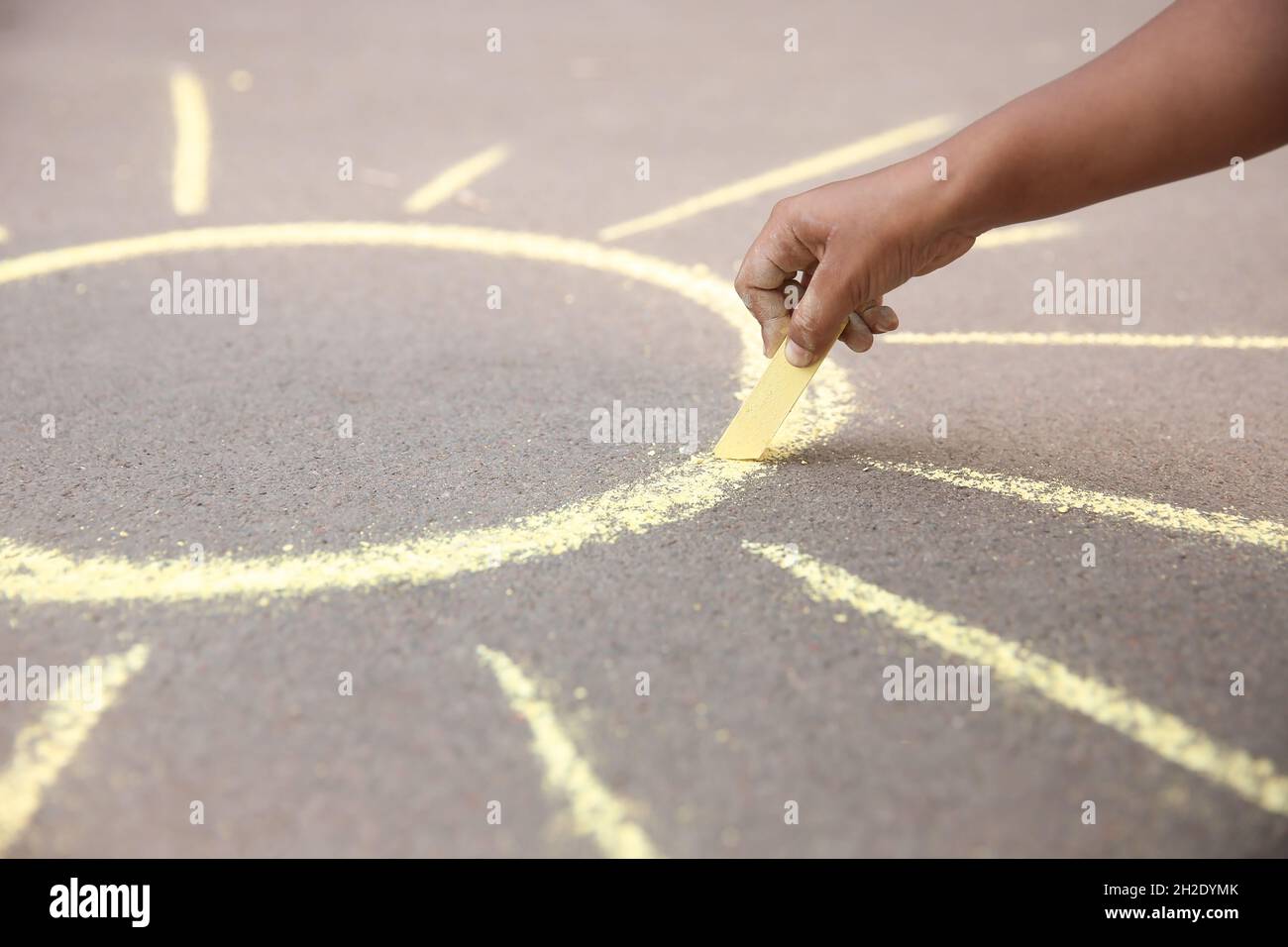 Little child drawing sun with chalk on asphalt Stock Photo - Alamy