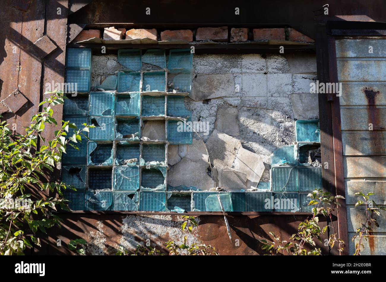 Wall of an old industrial building with broken glass panels and rusty ...