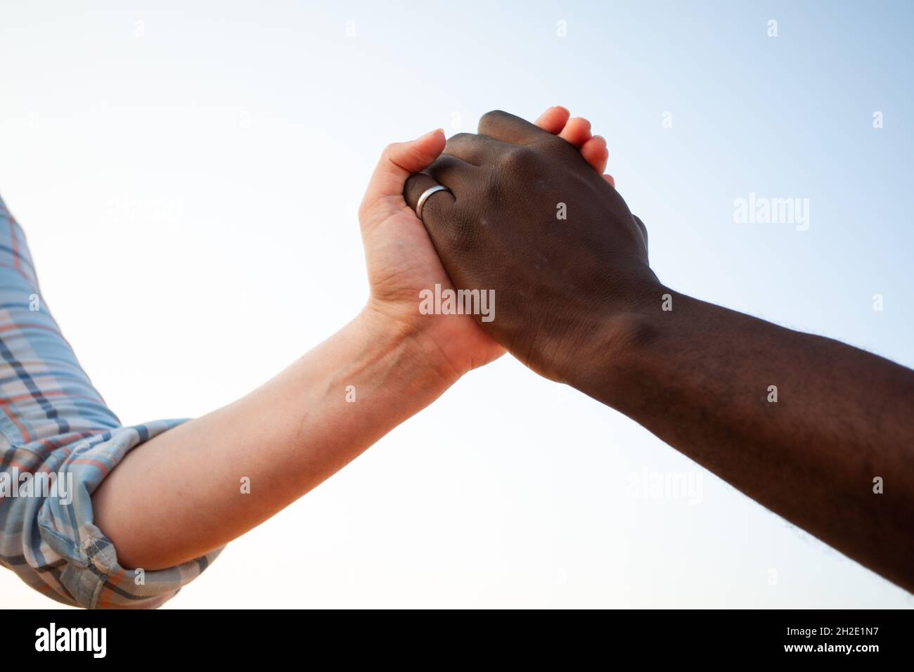 Multiracial relationship and friendsip concept. Two hands holding ...