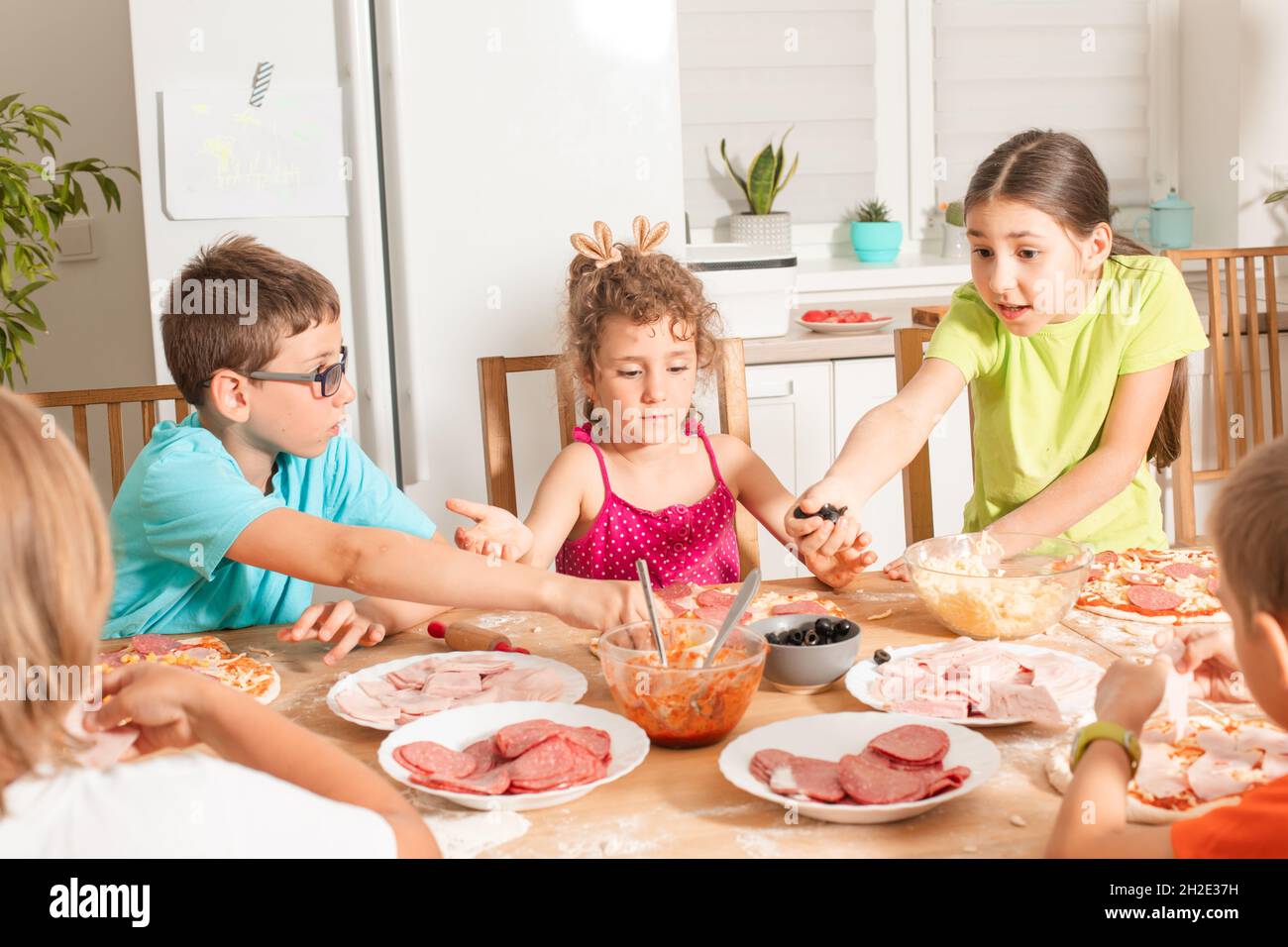 Friends together sit at a table in the kitchen and make pizza Stock ...