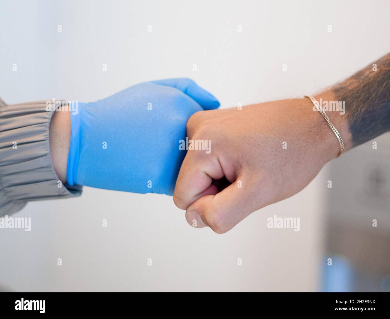 Closeup of two hands one with gloves and one without greeting each ...