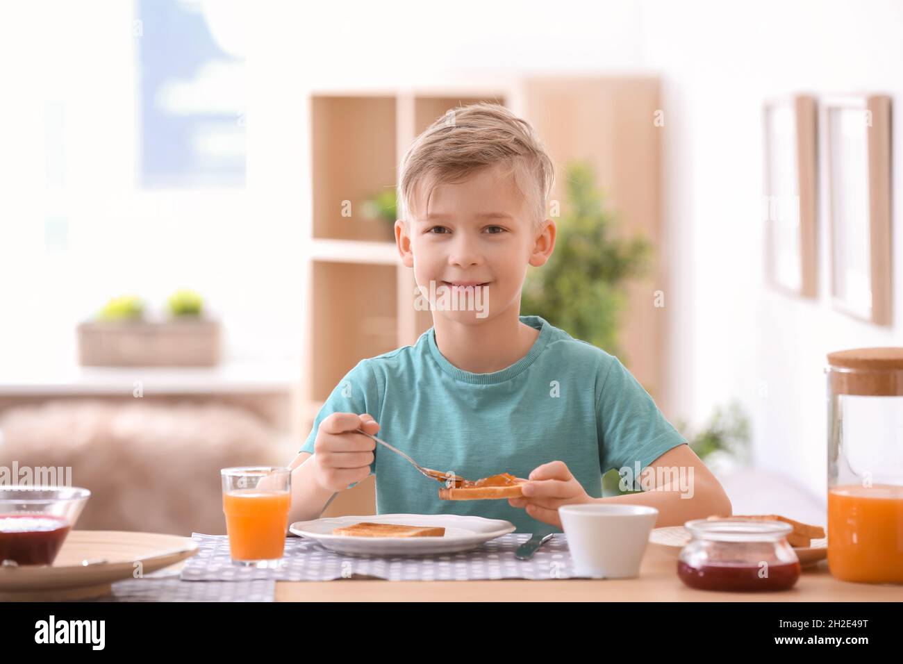 Cute little boy spreading jam onto tasty toasted bread at table Stock ...