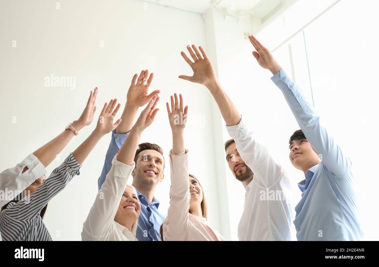 People raising hands together indoors. Unity concept Stock Photo - Alamy