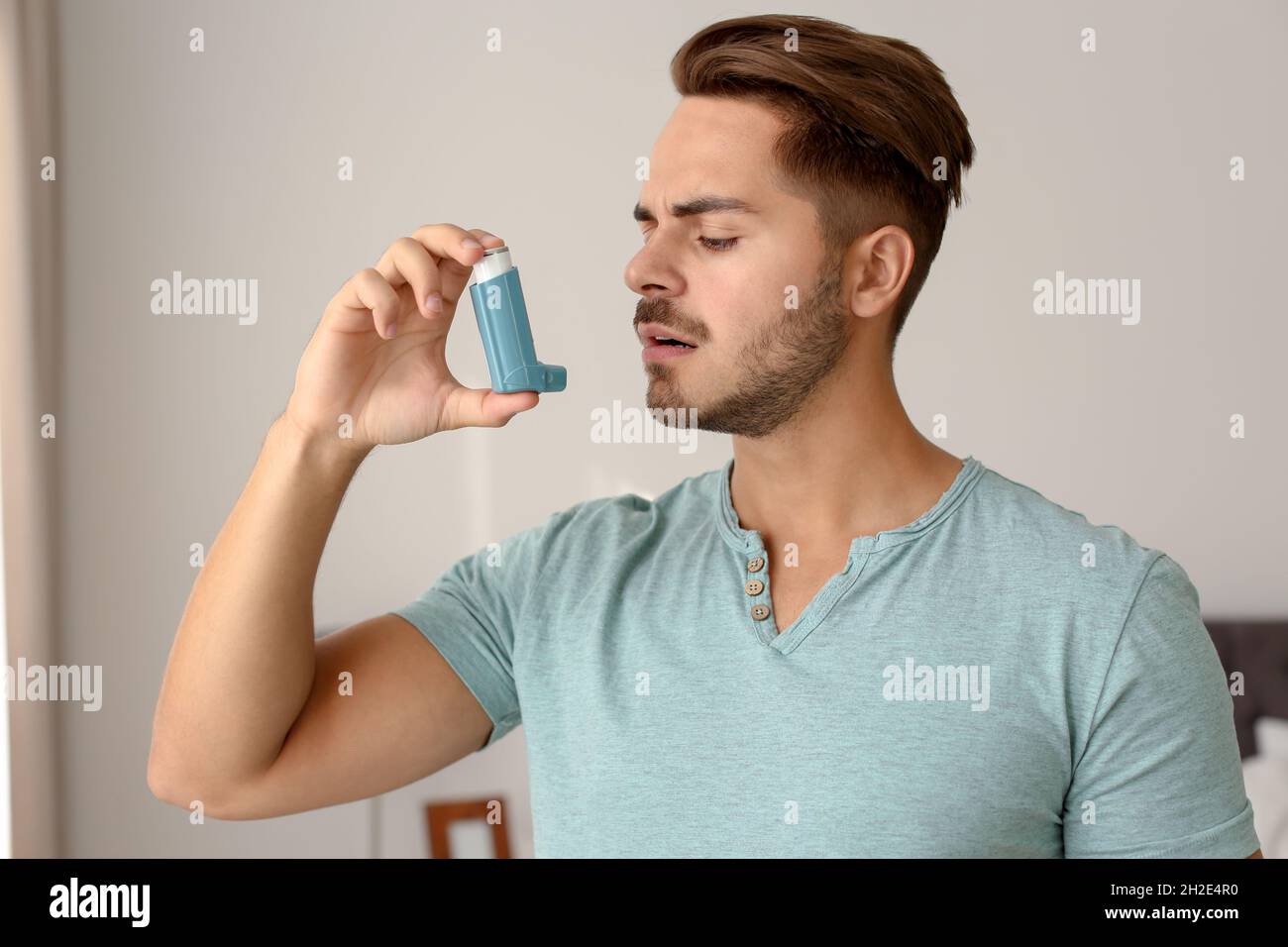 Young man using asthma inhaler at home Stock Photo - Alamy
