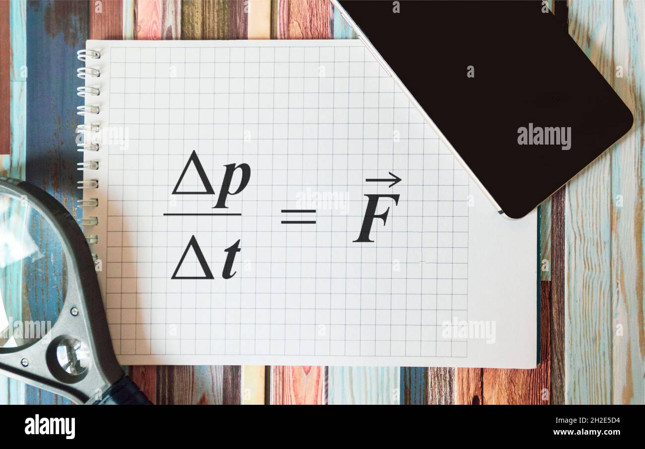 Newton's formula on a notebook, near a magnifying glass and a mobile ...