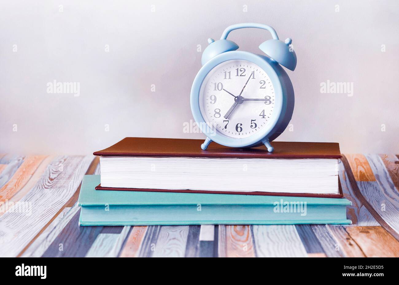 On a light striped background, there are two diaries and a blue alarm ...