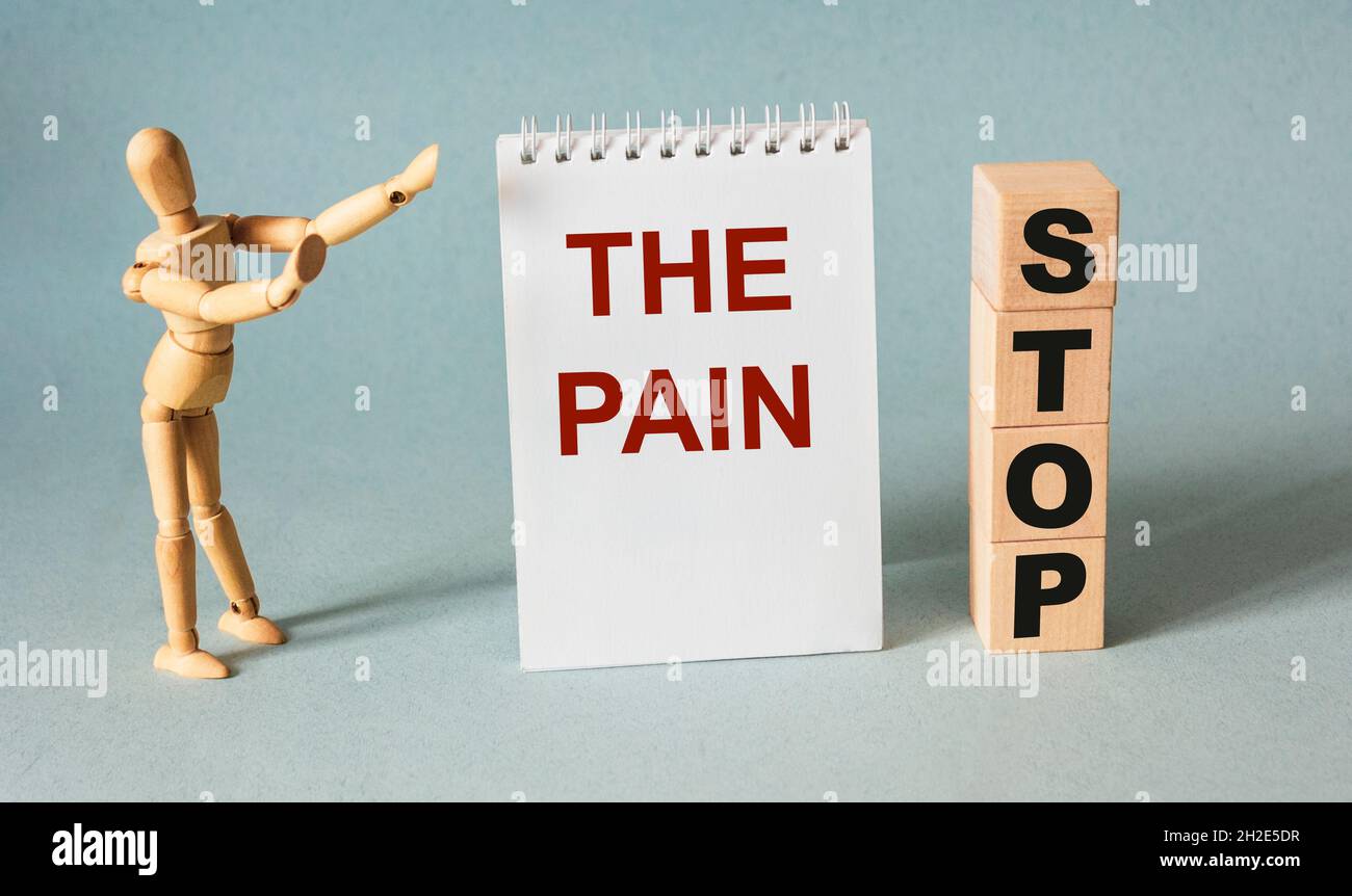 The text Stop Pain is written on a notebook and wooden cubes, next to a ...