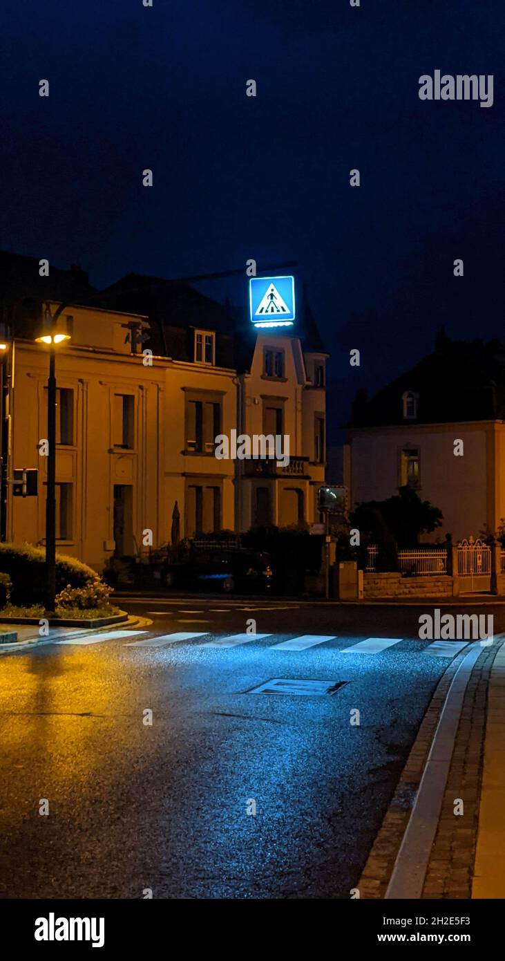 Pedestrian crossing sign on the side of the road at night in a ...