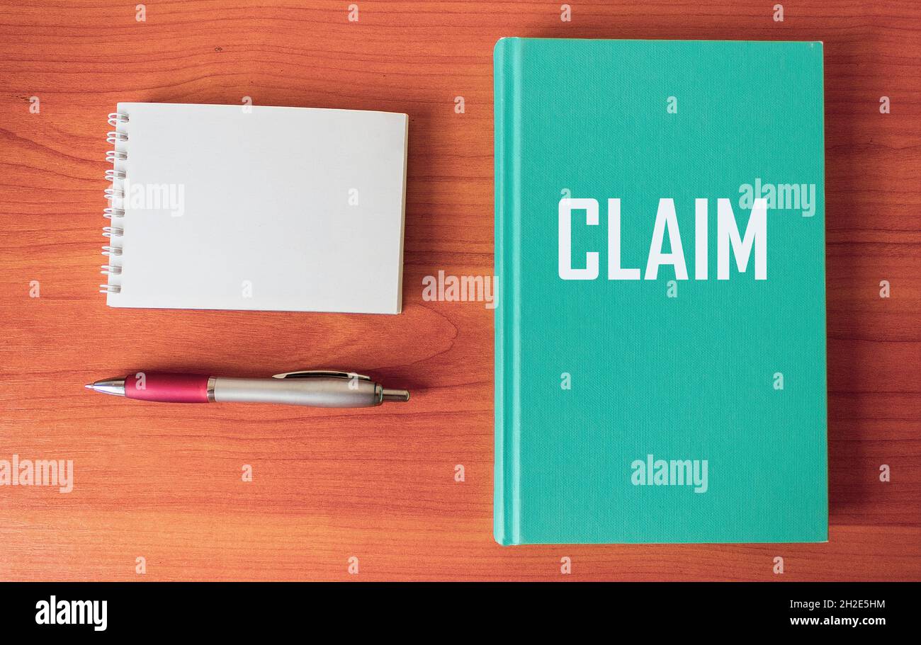 Claim, the word is written on a green notepad and a wooden table, next ...