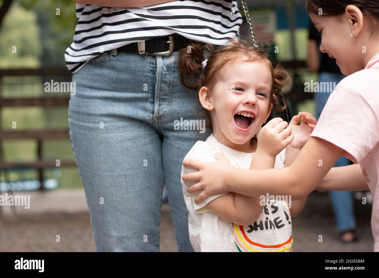 Little girls hugging while playing on the street against the background ...